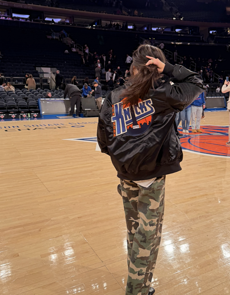 black satin New York Knicks bomber jacket with bold logo paired with camo cargo pants for a basketball game look%0A%0A